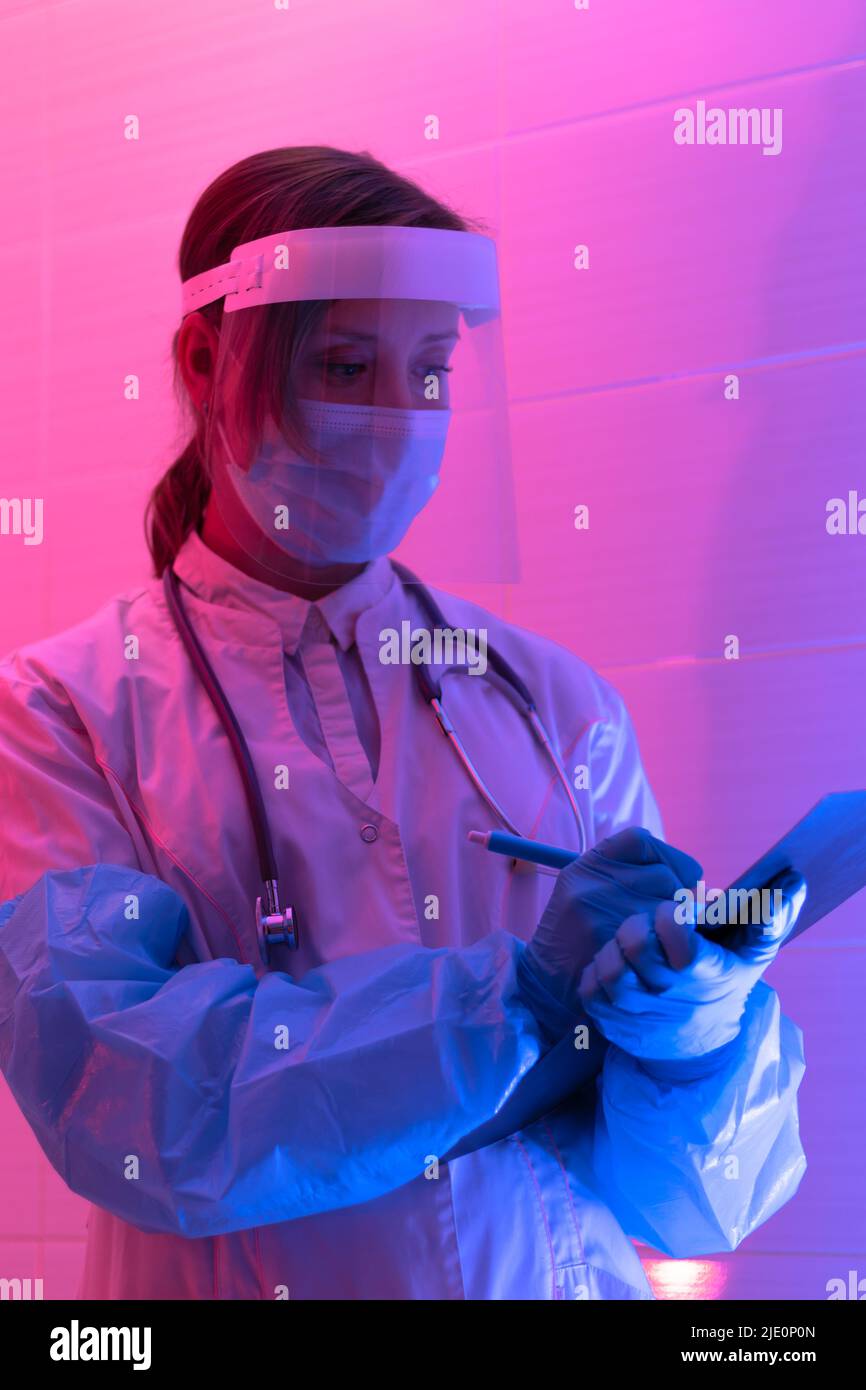 Beautiful young woman doctor with documents and a pen in a protective ...