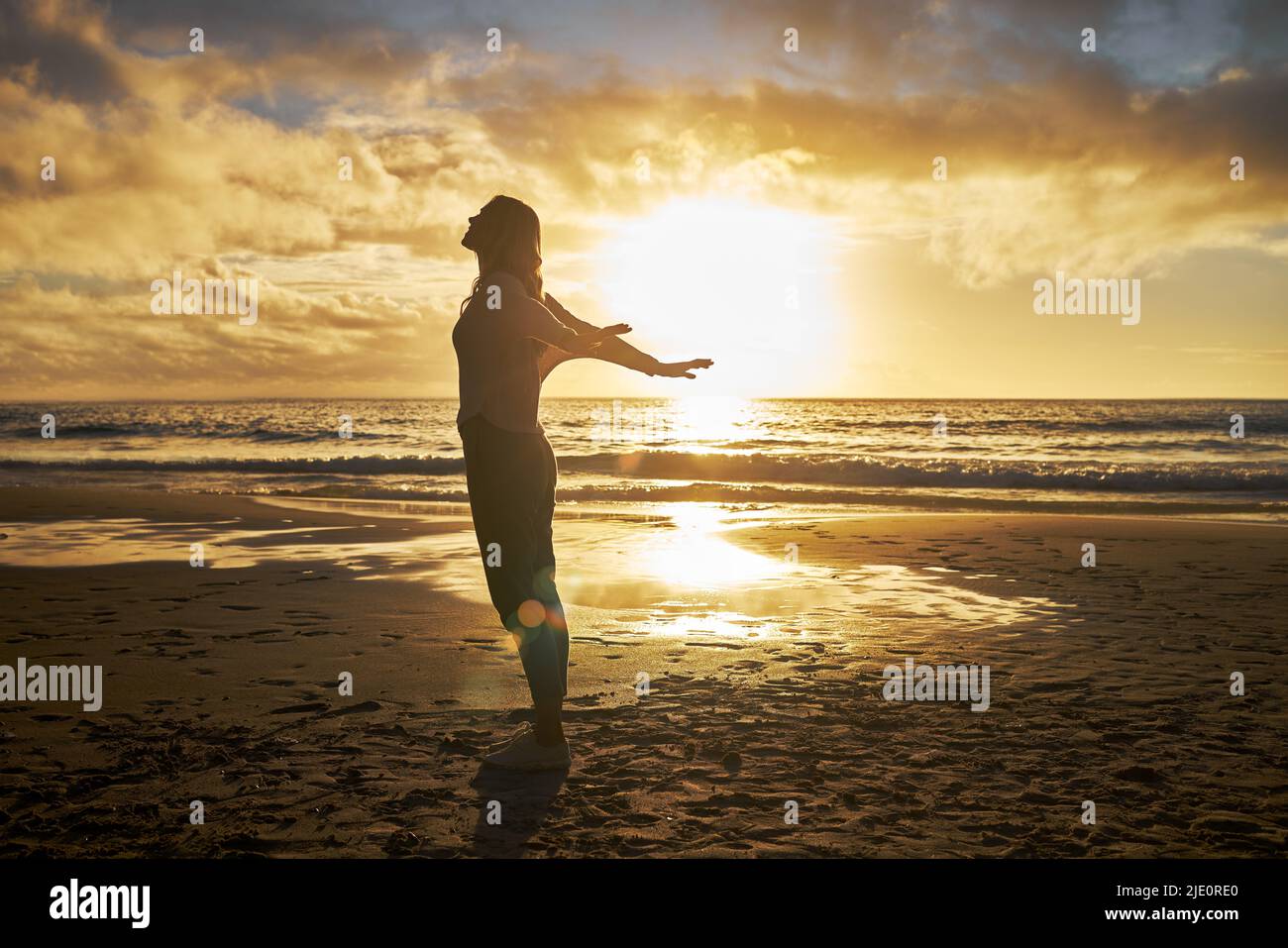 Rear View of a silhouette woman stretching with her arms out at the ...