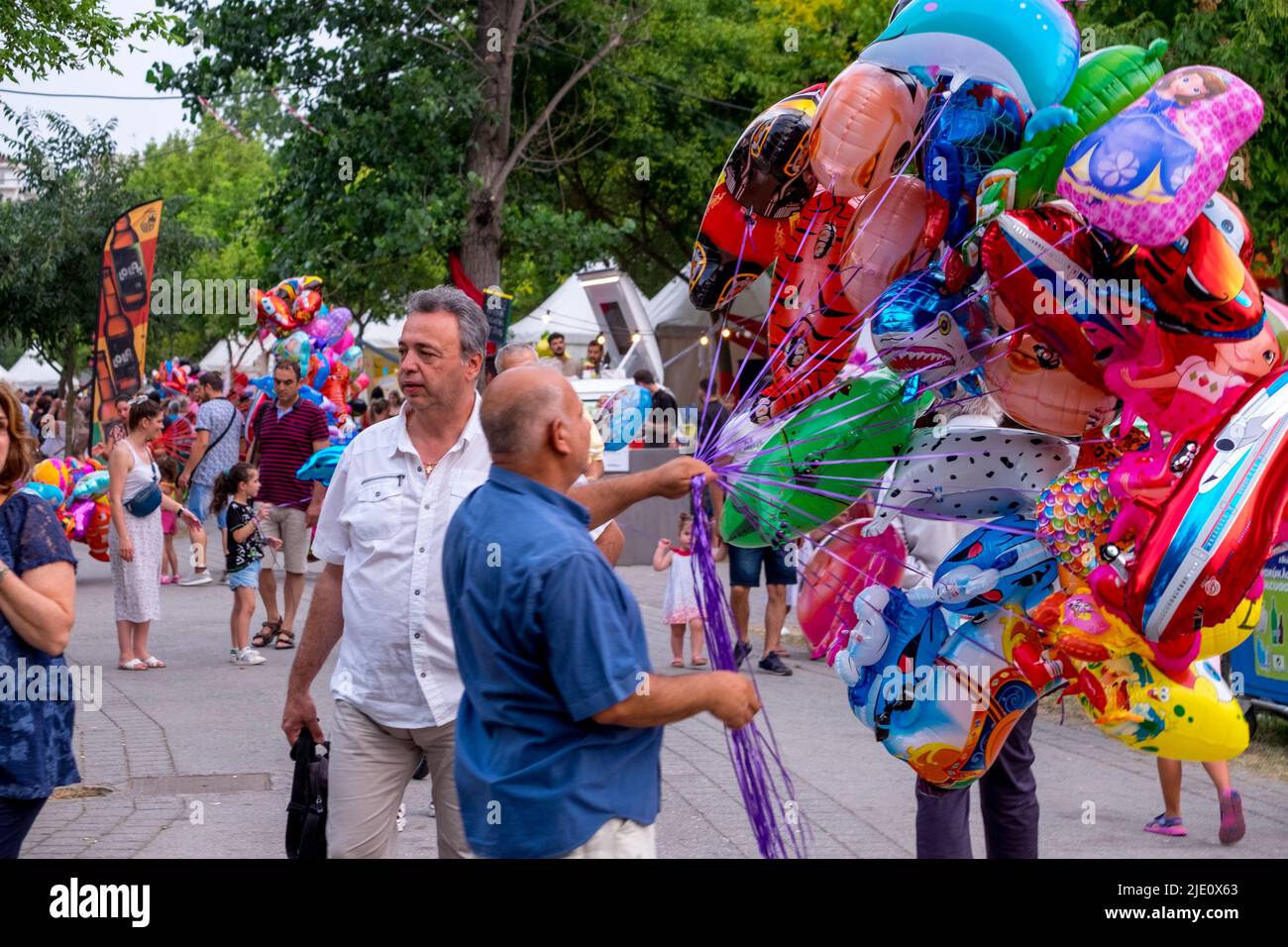A man selling balloons on asidewalk during a festival or event Stock ...