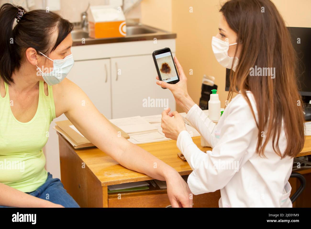 Dermatologist showing cropped image of mole to patient using modern ...