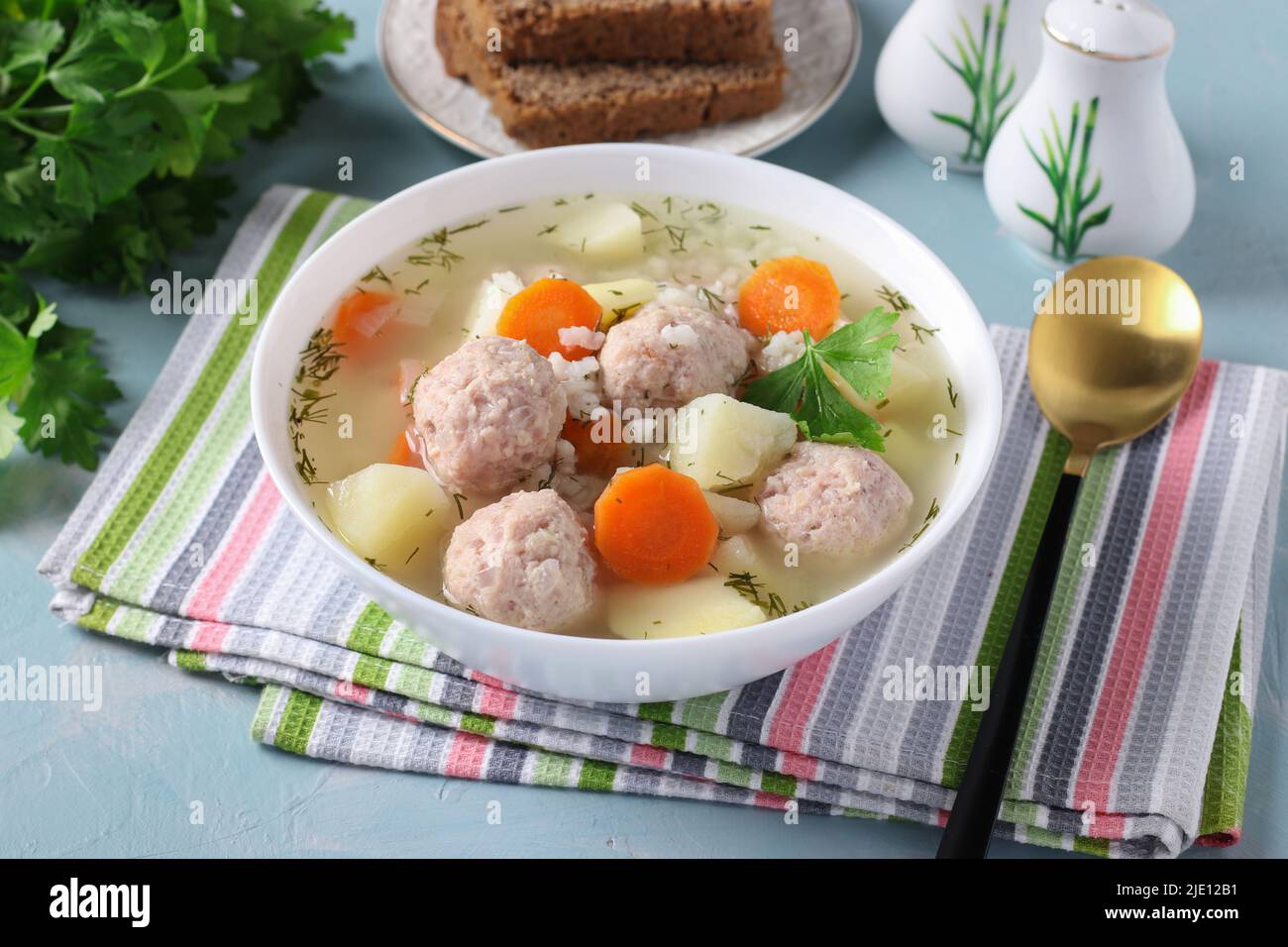 Soup with chicken meatballs, rice and vegetables in a white bowl on a ...