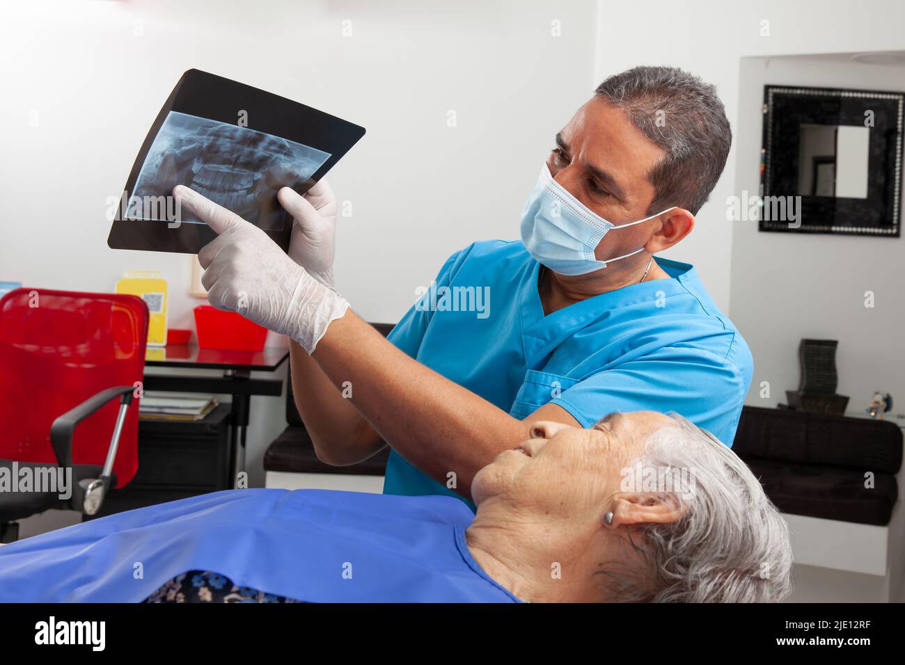 Male middle -aged dentist at his office using an x ray image to explain ...