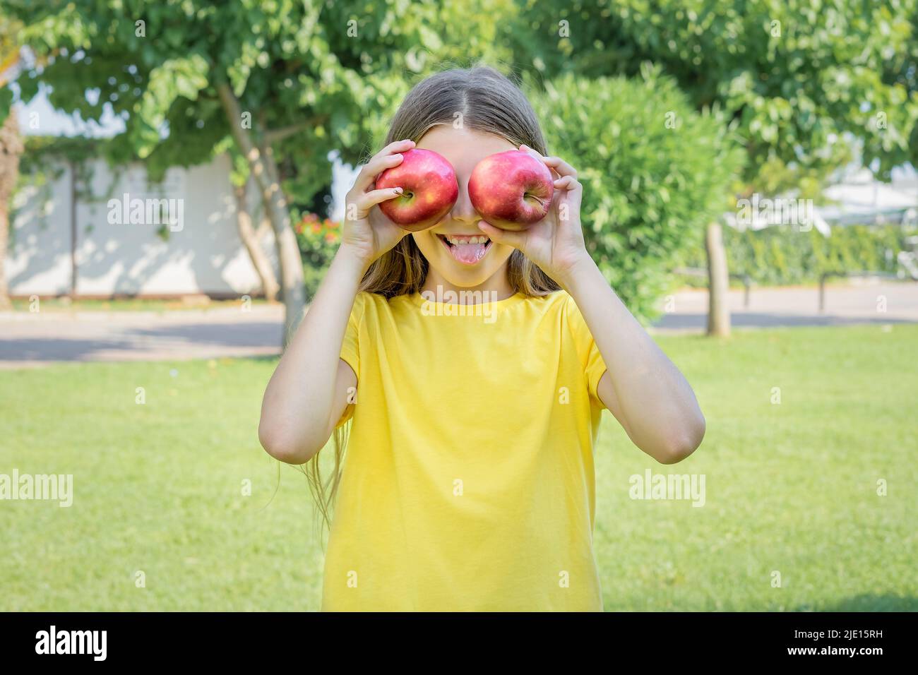 A teenage girl holds two apples in front of her face in the park Stock ...