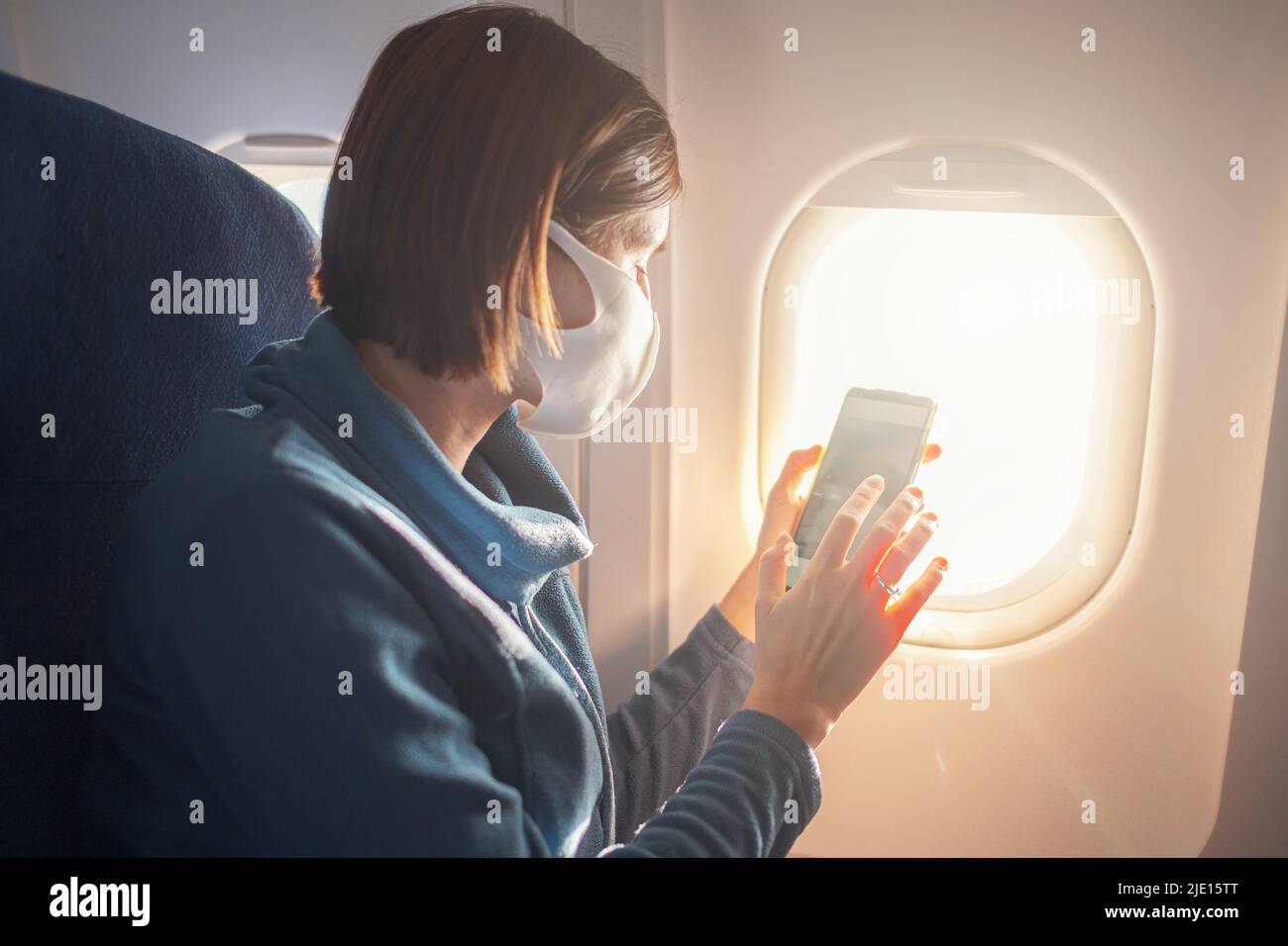 Young beautiful woman sitting at window of plane during the flight. new ...