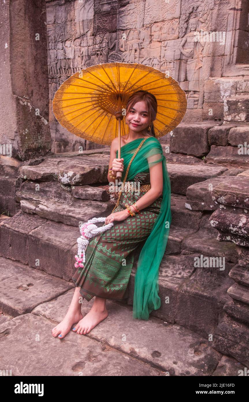Cambodian woman in traditional clothing holding umbrella at The Bayon ...