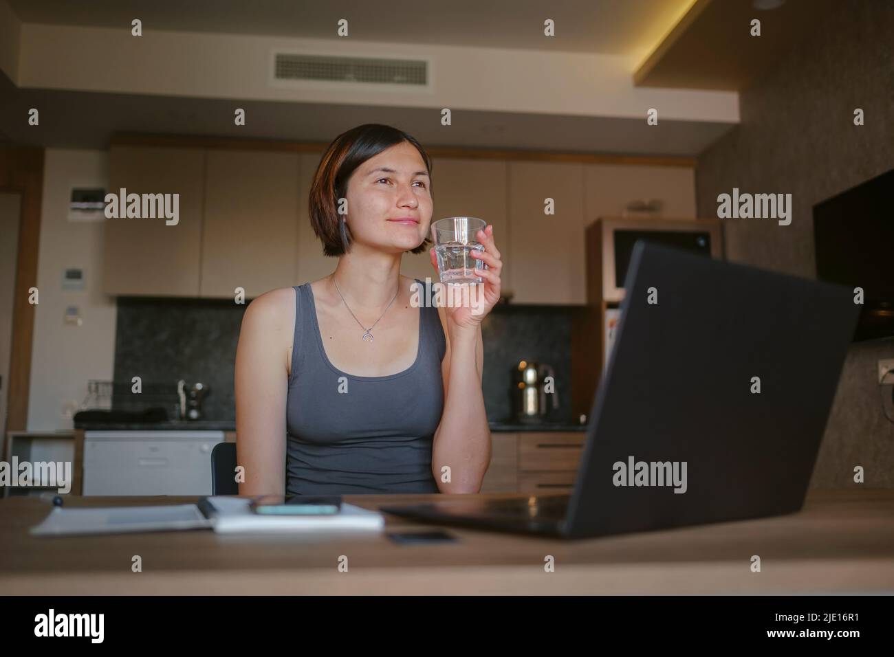 Shot of beautiful asian woman working with laptop while drinking glass ...