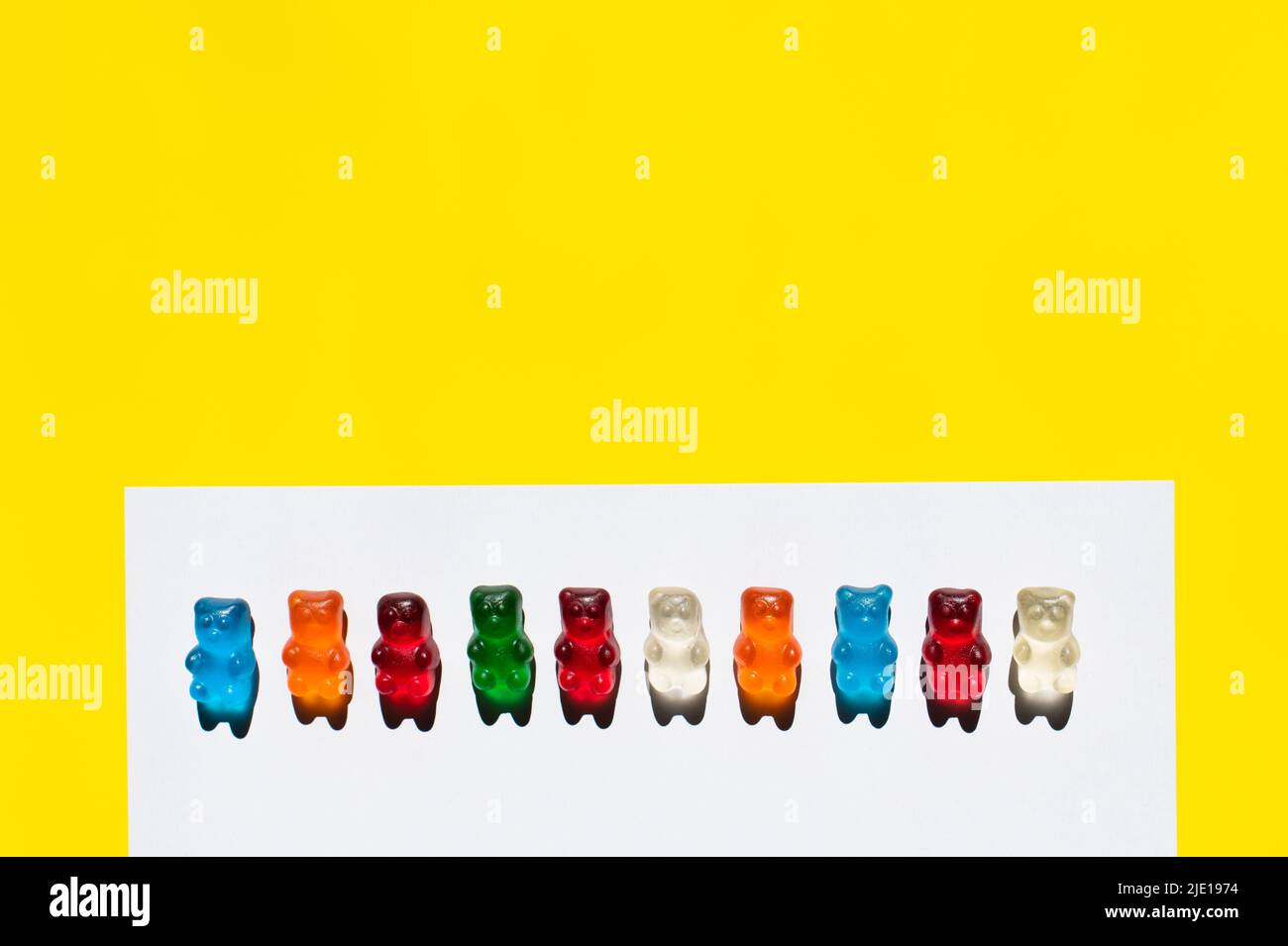 Top view of row from gummy bears on white and yellow Stock Photo - Alamy