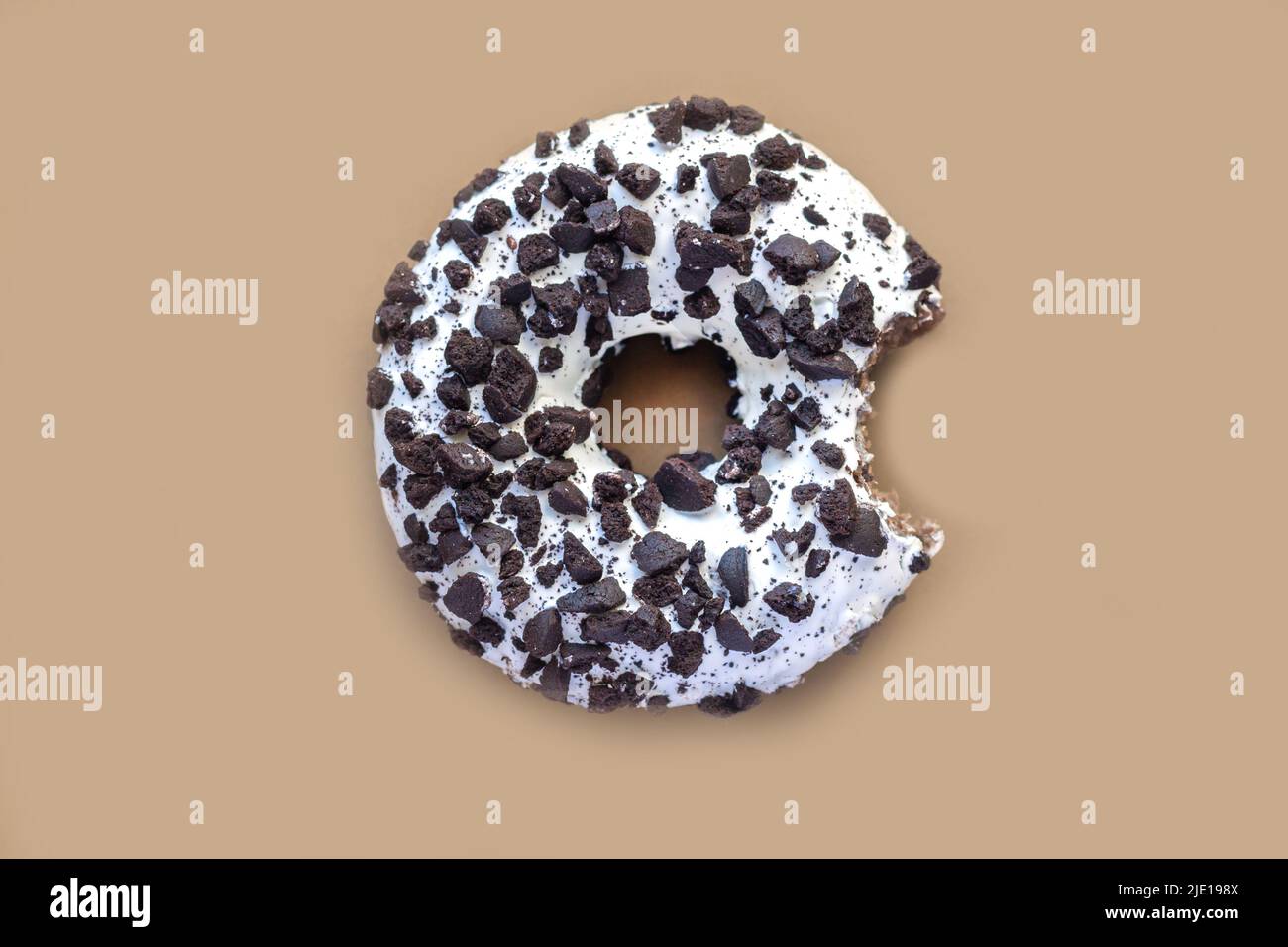 Tasty glazed chocolate donut with bite missing on brown background. Top ...