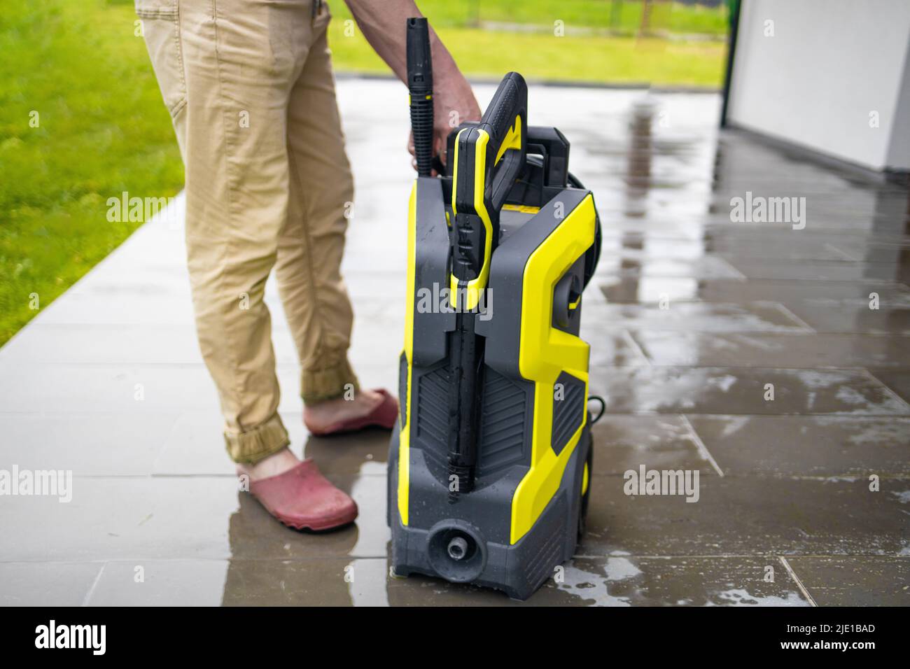 Pressure washer cleaning machine on wet concrete floor near the house ...