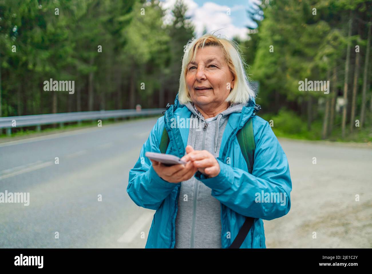 Female hand holds a phone with navigator location point on a road ...