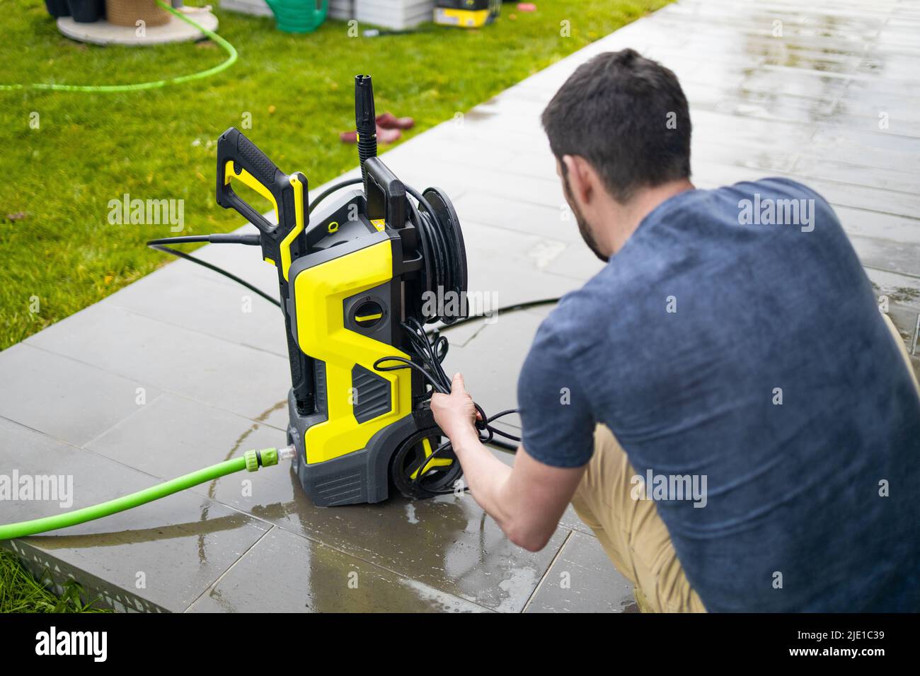 Pressure washer cleaning machine on wet concrete floor near the house ...