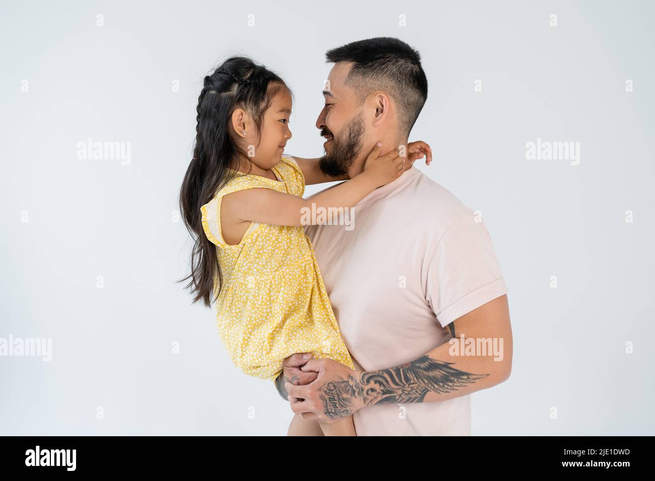 side view of cheerful father and daughter looking at each other ...