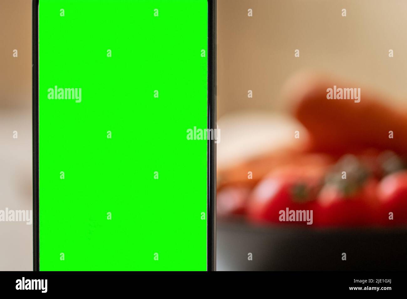 smartphone with a green screen on a blurred background of a plate with ...