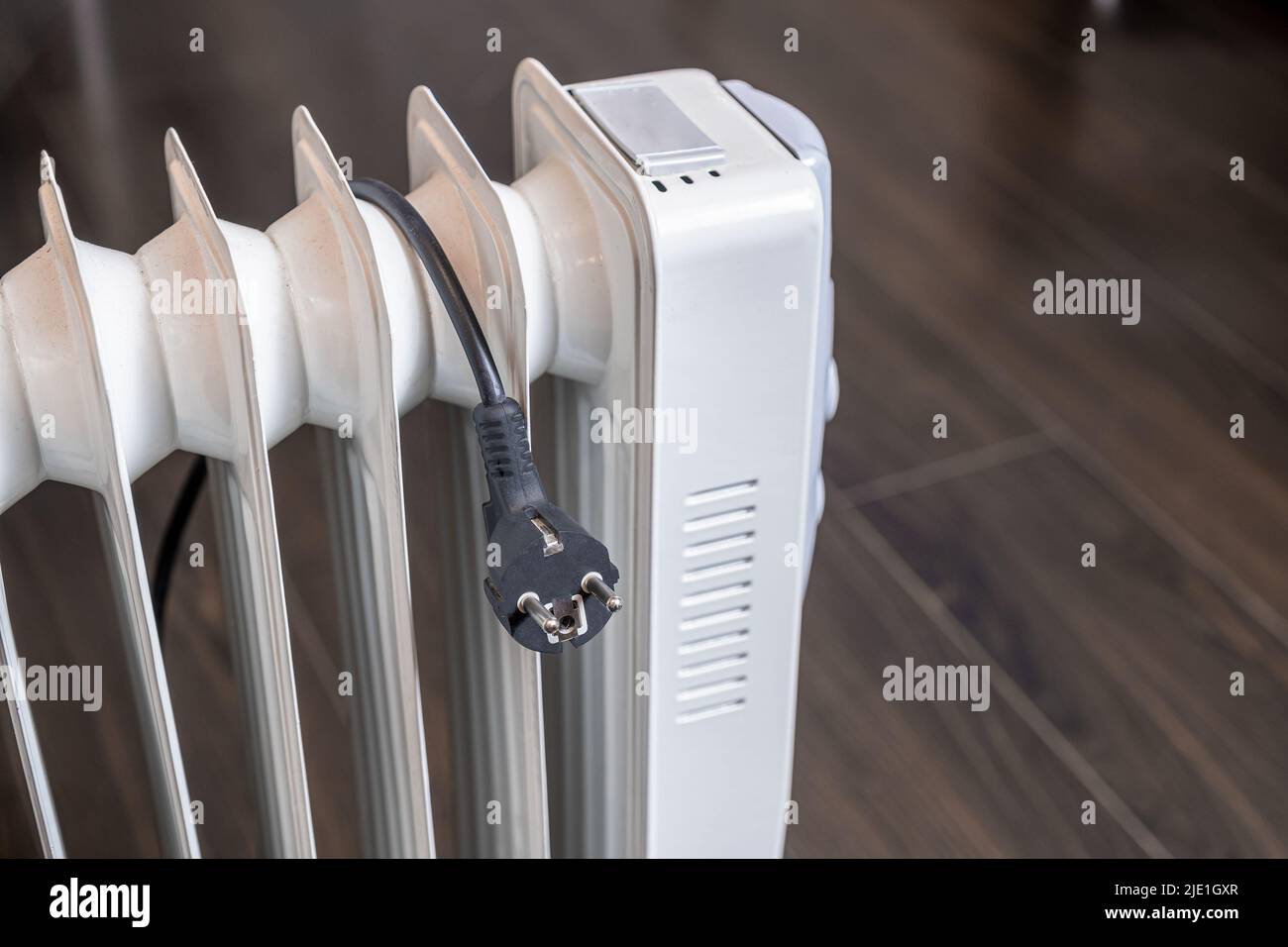 a wire with a plug lies on a white electric heater. saving electricity ...