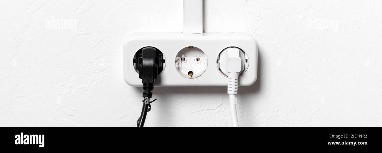Group of white european electrical outlets with two plugs inserted into ...