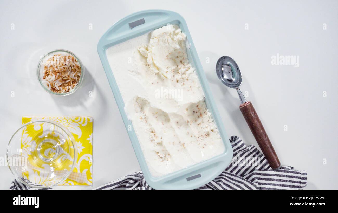 Flat lay. Scooping homemade coconut ice cream into a glass ice cream ...