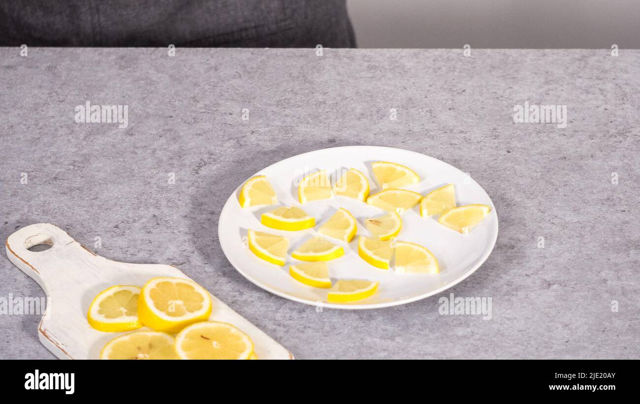 Step by step. Slicing organic lemon wedges on a white plate Stock Photo ...