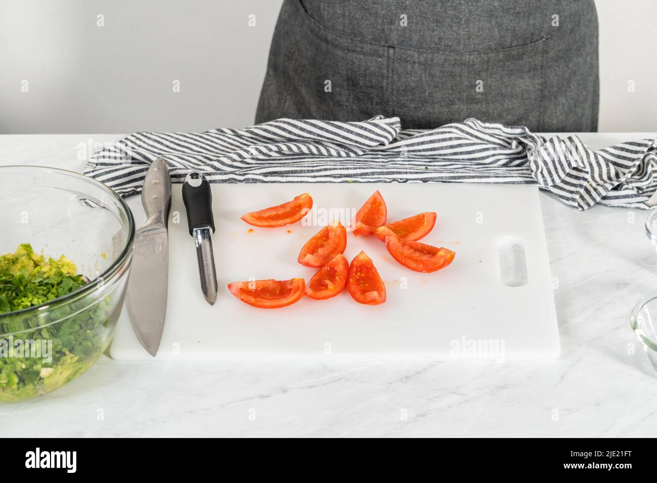 Cutting ingredients on a white cutting board to make classic guacamole ...