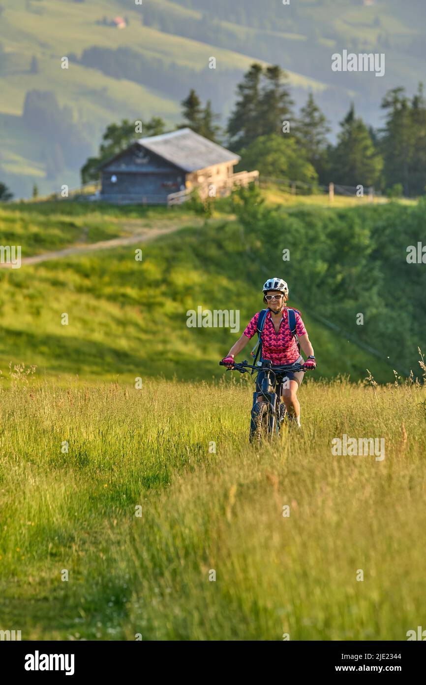 pretty senior woman riding her electric mountain bike on the mountains ...