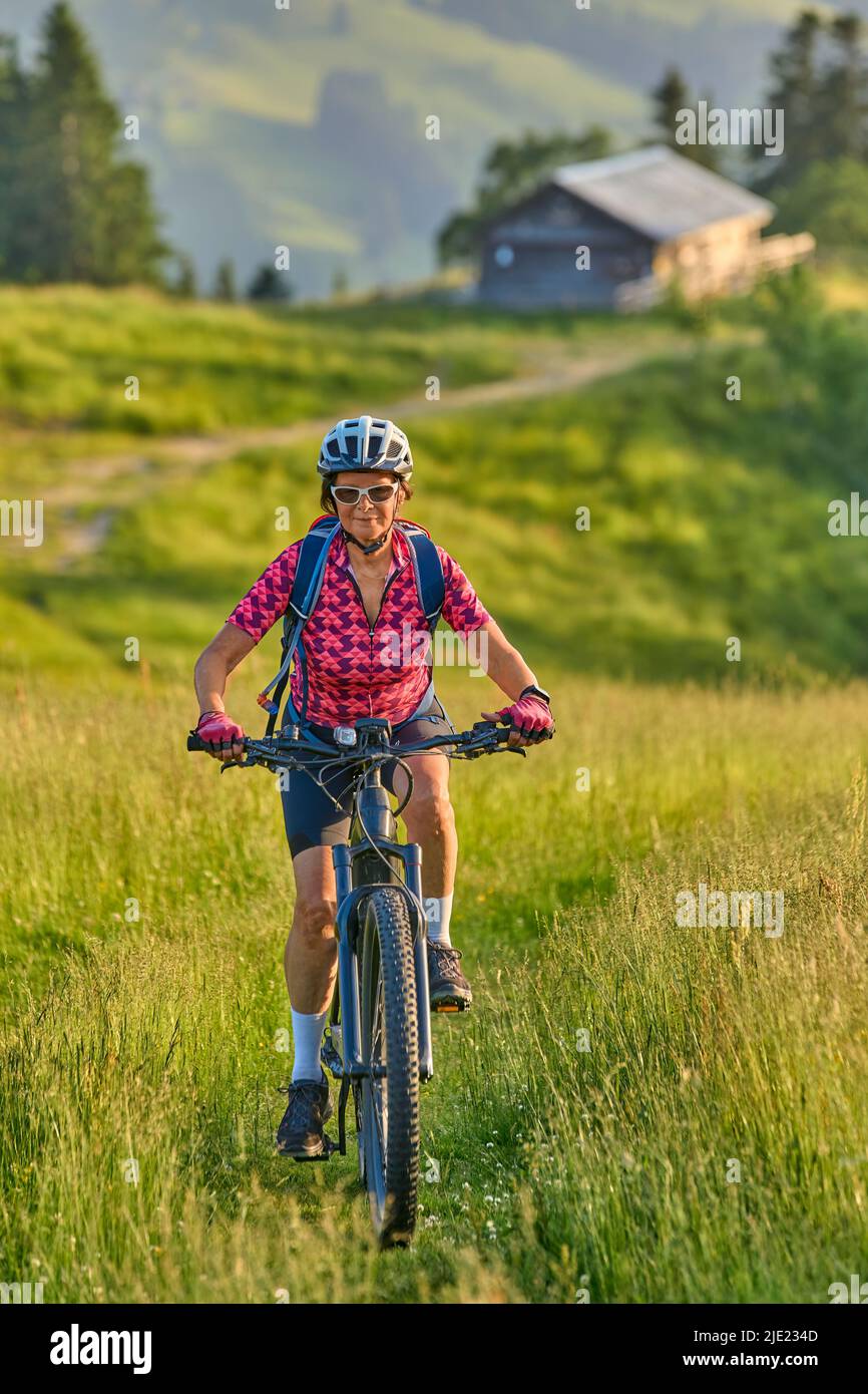 pretty senior woman riding her electric mountain bike on the mountains ...