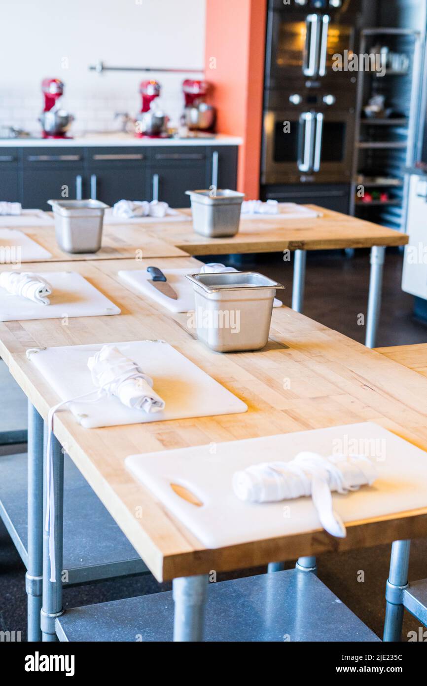 Tables prepared with white cutting boards and aprons for cooking class ...