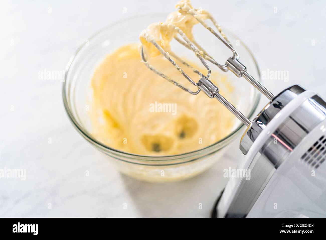Mixing ingredients in a large glass mixing bowl to make the cream ...