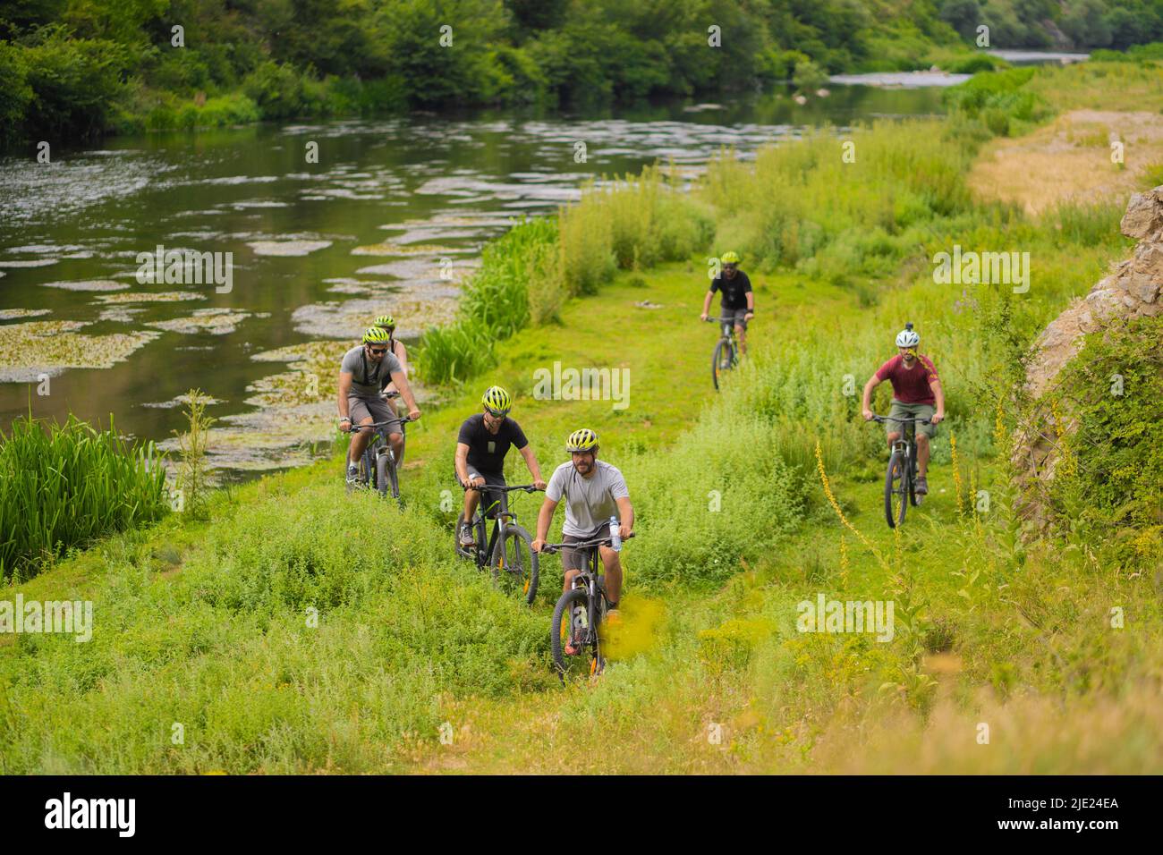 Group of happy and sportive friends are riding their bikes together ...