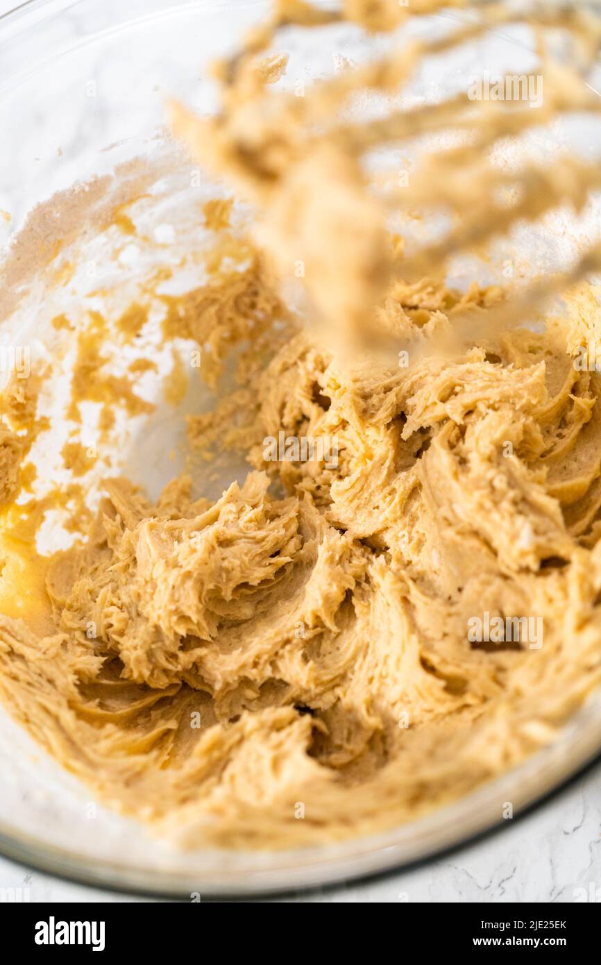 Mixing ingredients with a hand mixer to bake eggnog cookies with a ...