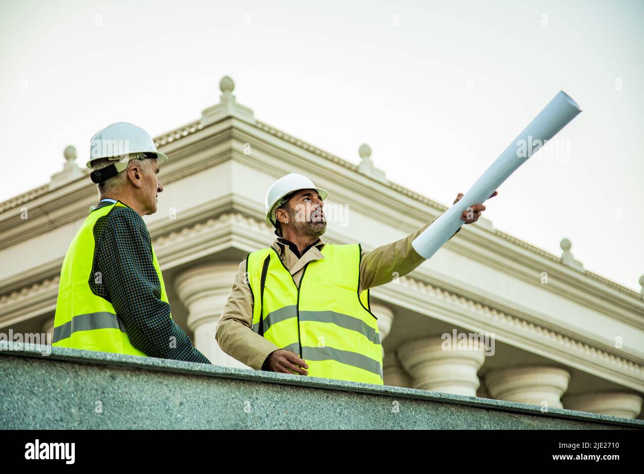Two senior construction workers are looking and thinking while talking ...