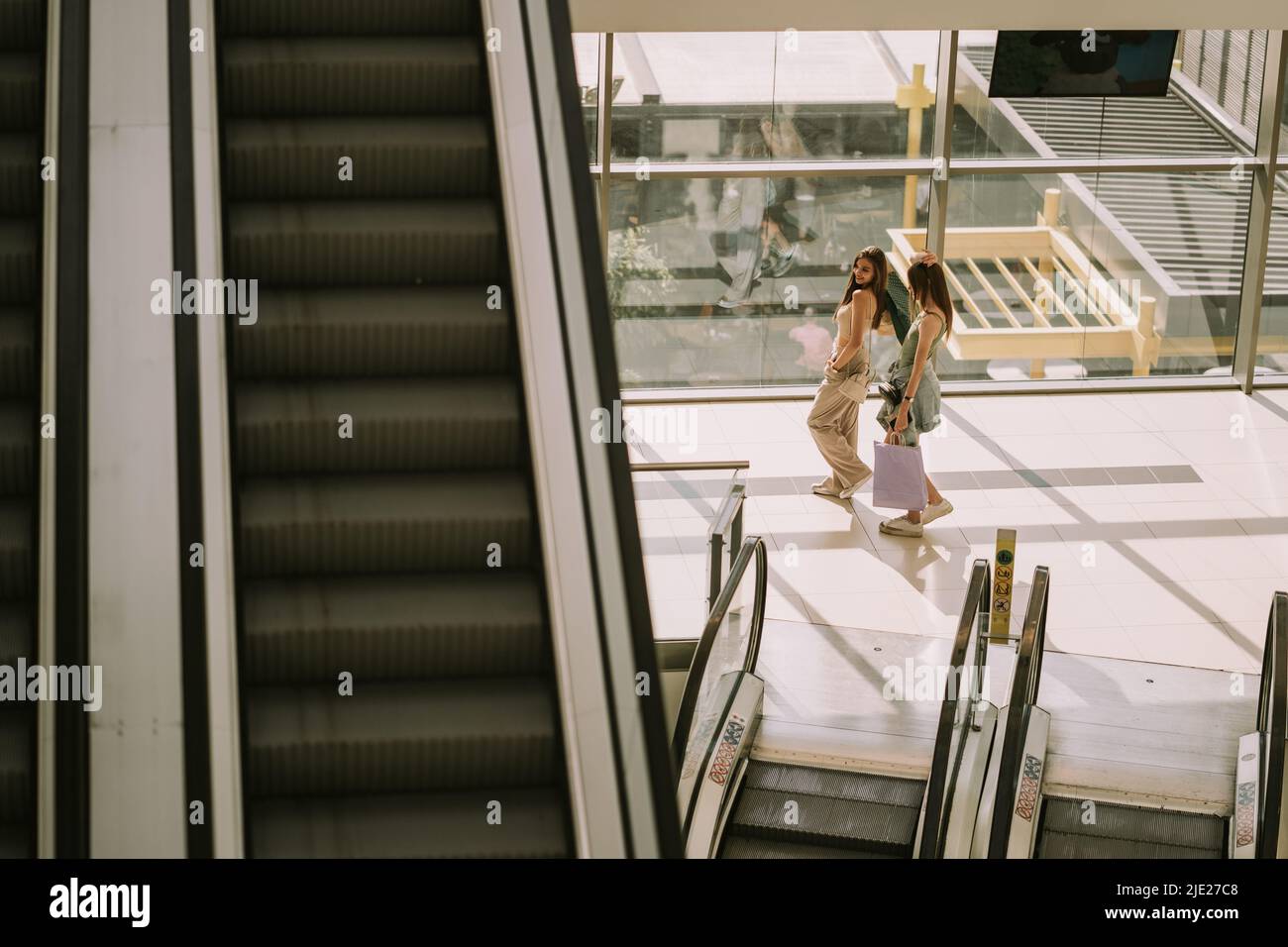 Two beautiful girls walking with their shopping bags in the mall near ...