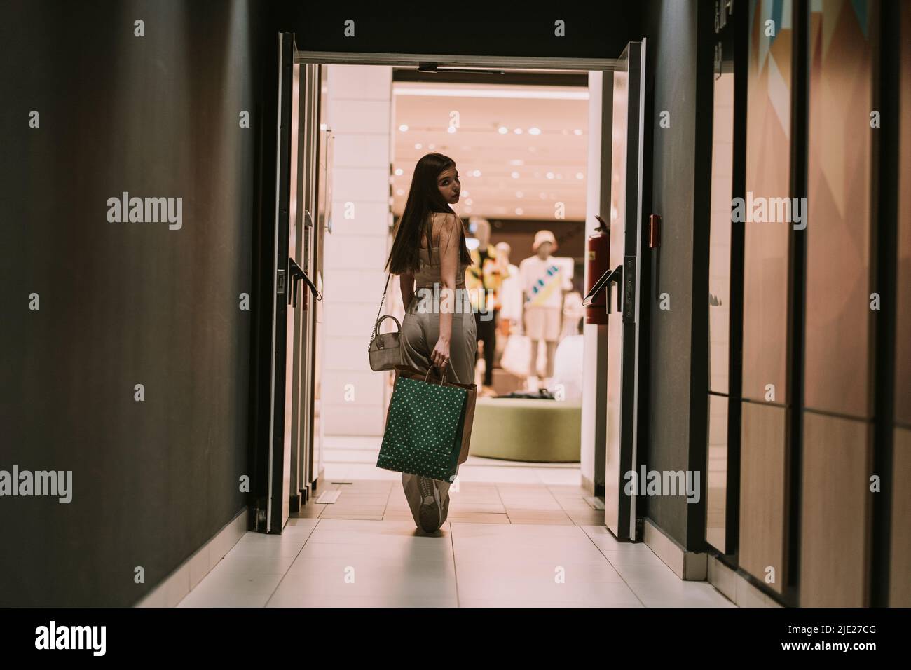 Pretty girl walking in the middle of the hallway while looking back ...