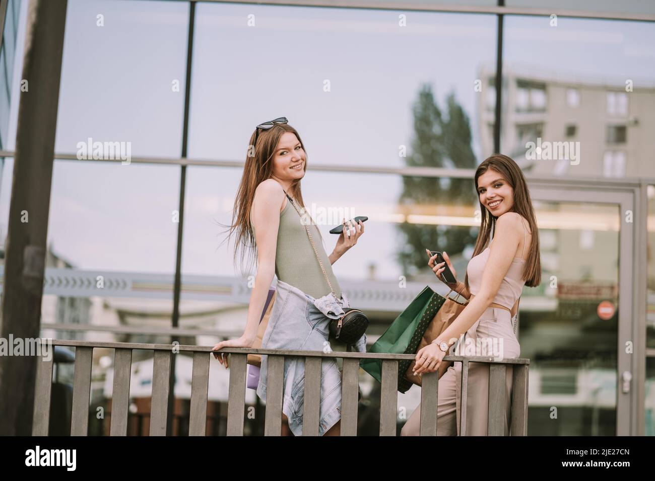Two pretty girls standing outside infront of the mall with their ...