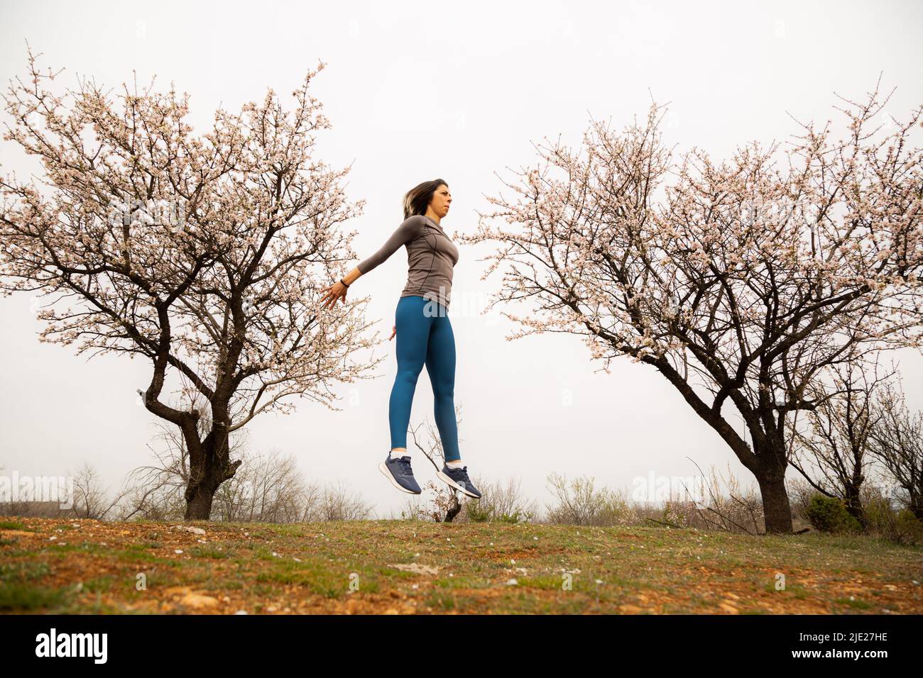 Girl is jumping in nature in between trees Stock Photo - Alamy