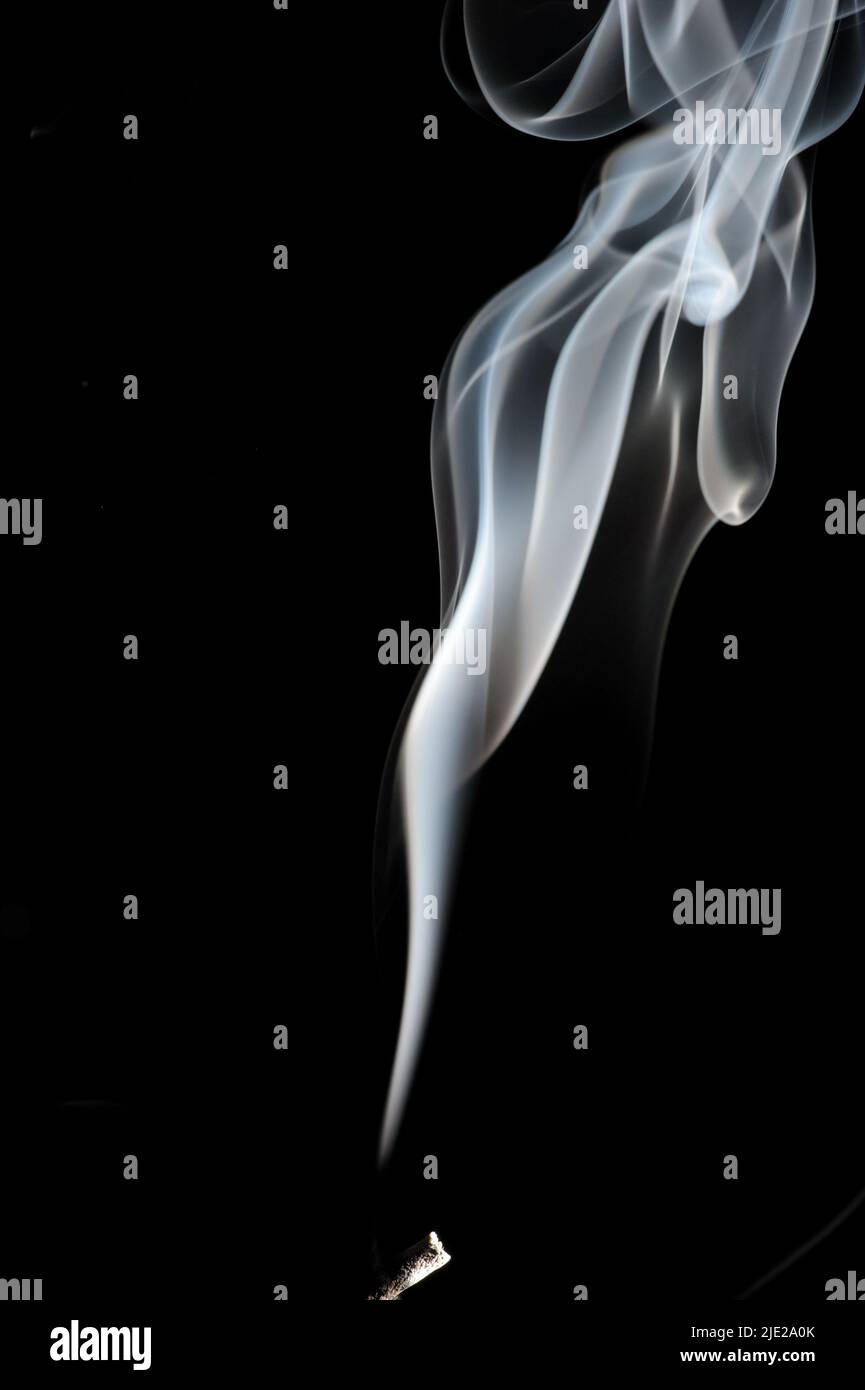 Puffs and curls of white smoke against a black background rising from a ...