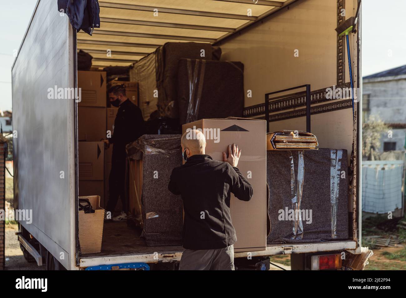 2 men placing bundles inside a moving truck Stock Photo - Alamy