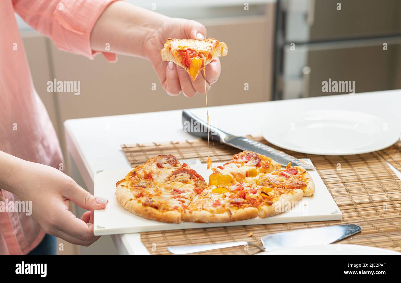 separation of a piece of homemade pizza served on a plate by female ...