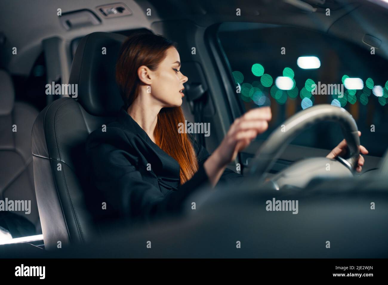 horizontal photo of a nice woman in a black shirt driving a car while ...