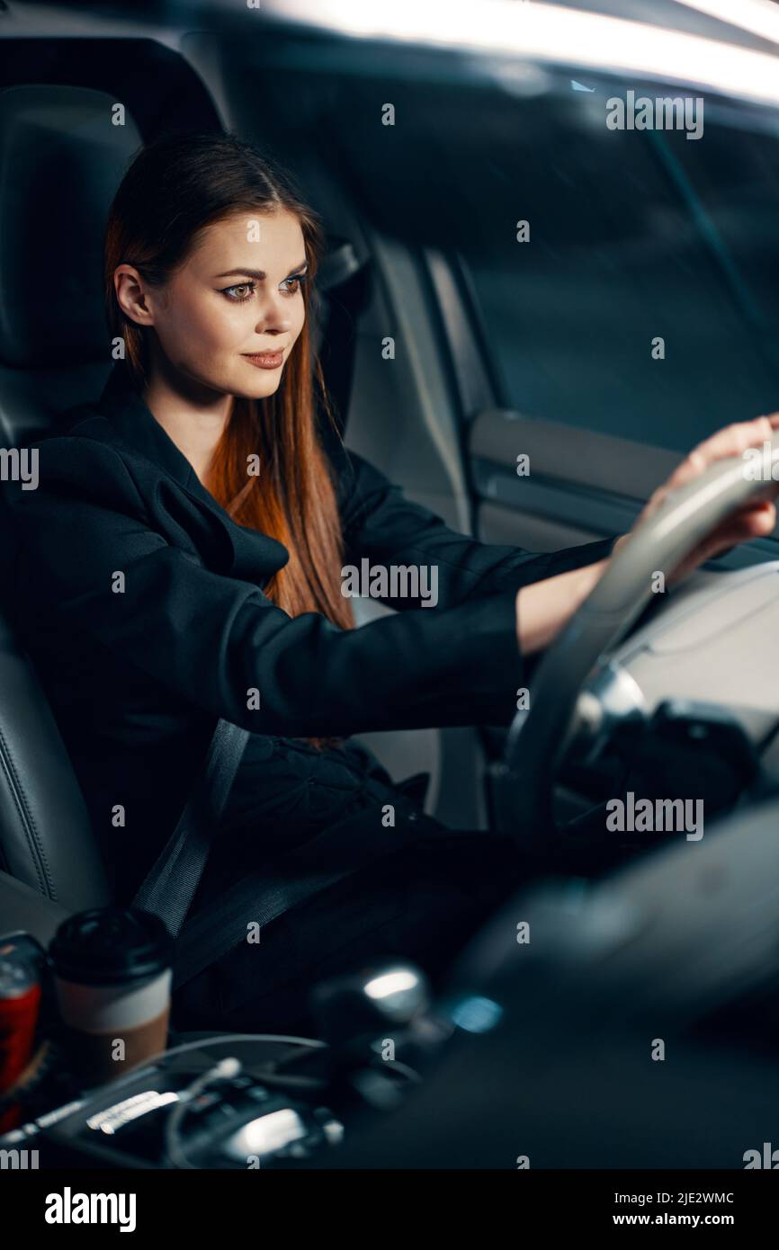 vertical photo of a pleasant, relaxed woman sitting behind the wheel of ...