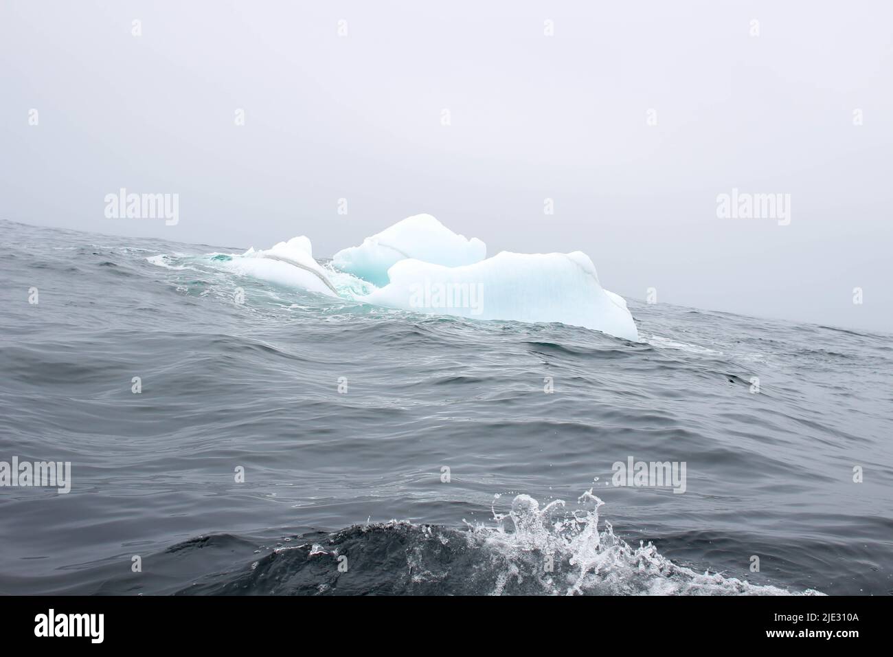 Wave crashing against small iceberg bit floating in sea Stock Photo - Alamy