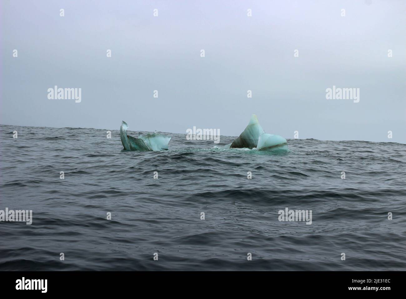 Wave crashing against small iceberg bit floating in sea Stock Photo - Alamy