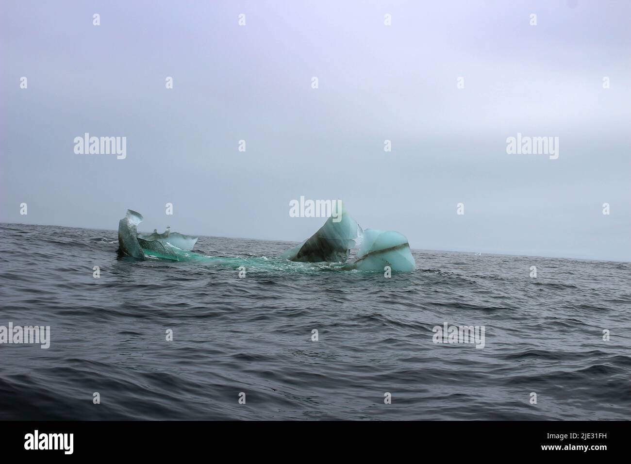 Wave crashing against small iceberg bit floating in sea Stock Photo - Alamy