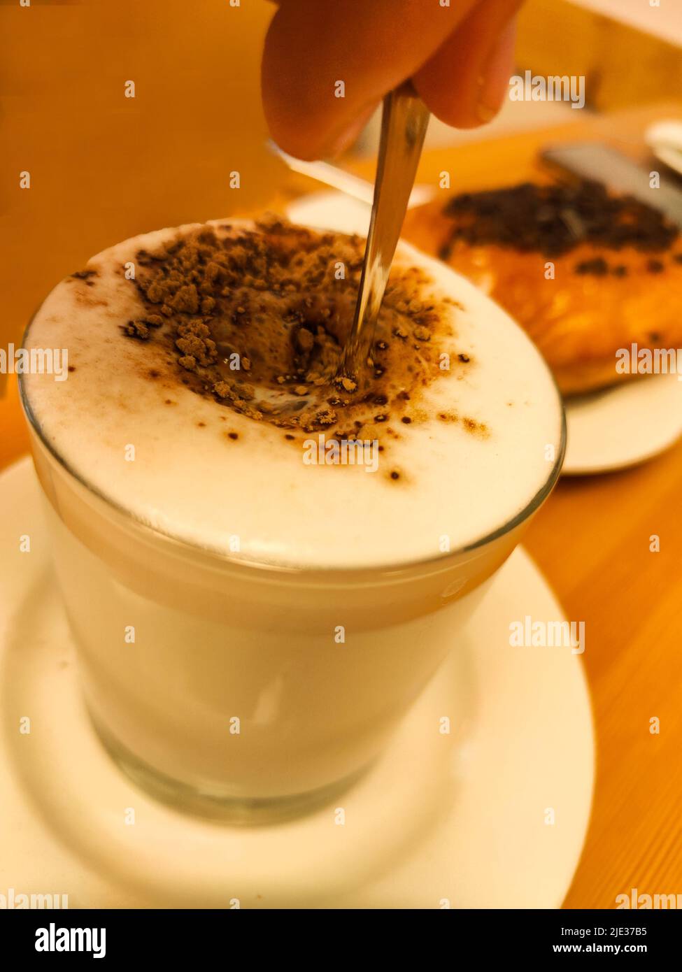 detail of a person stirring with a spoon the milk and cocoa for a ...