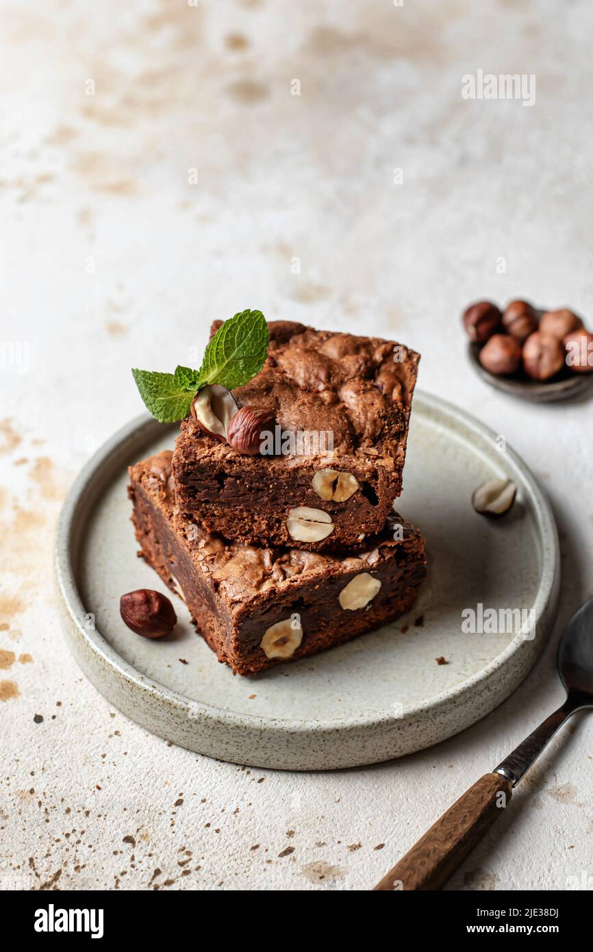 Stack of chocolate brownies with hazelnuts and mint leaf on a plate ...