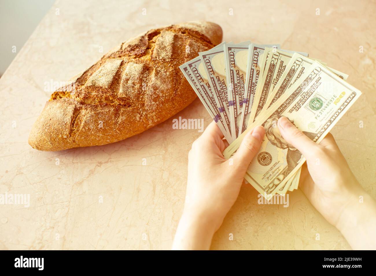 Woman Counts Dollars In Her Hands On The Background Of A Loaf Of Bread