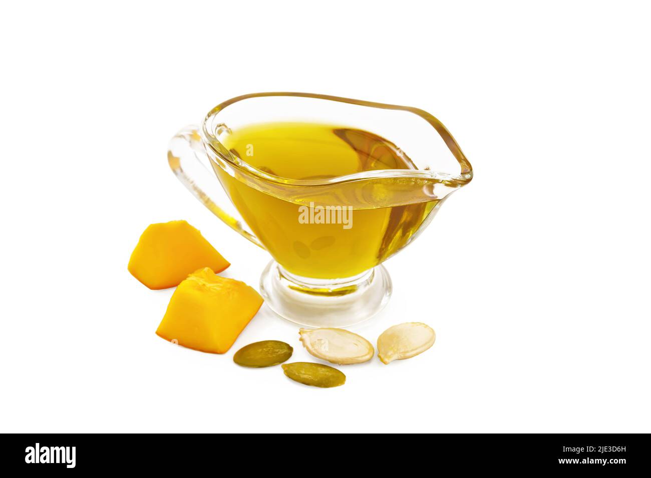 Pumpkin seed oil in a glass gravy boat, seeds and vegetable pieces ...
