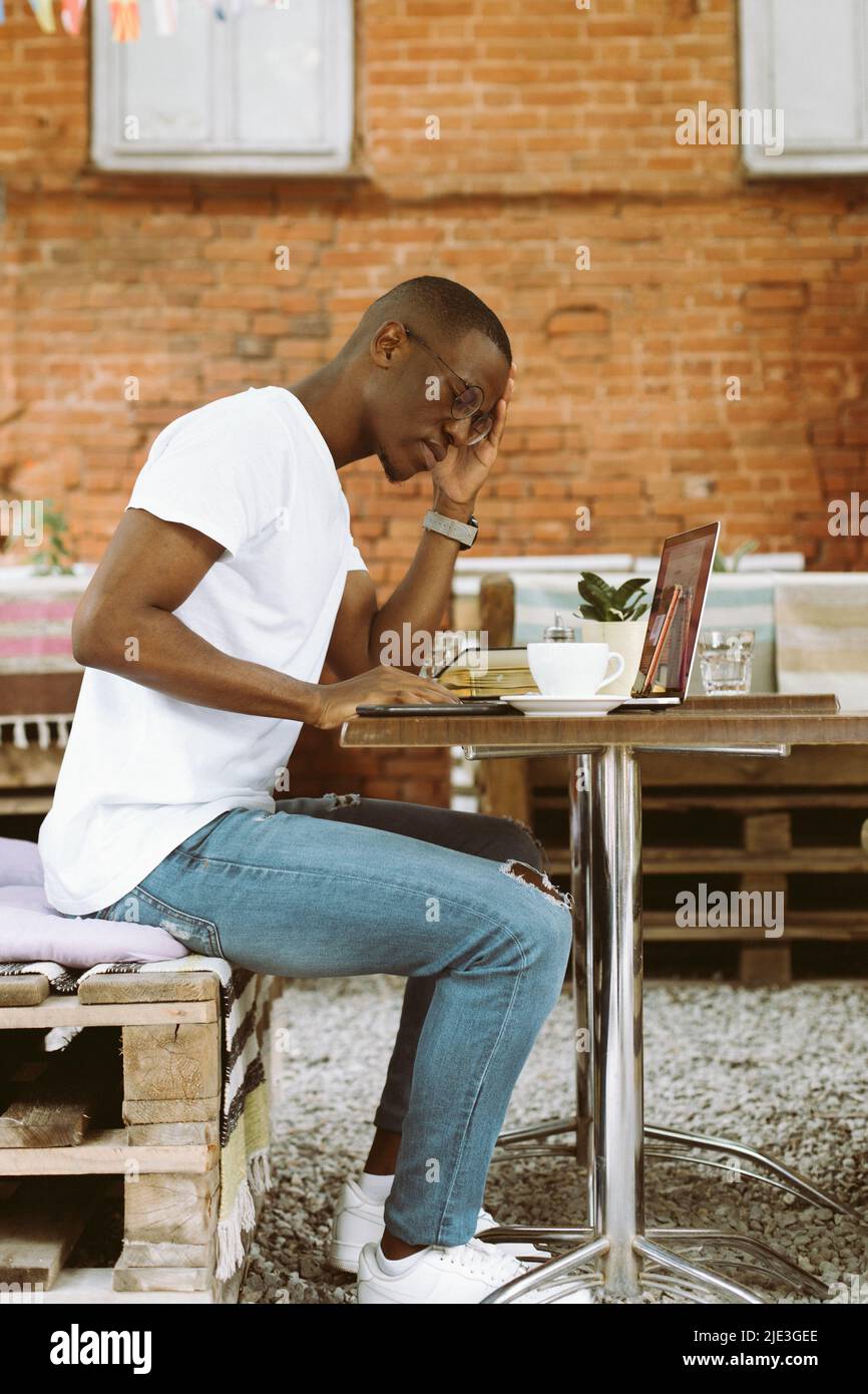 Vertical multicultural businessman with laptop, phone in coffee shop ...