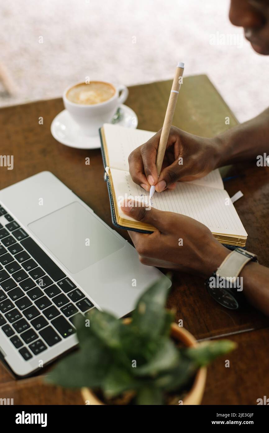 Vertical cropped multiracial businessman using laptop, taking notes in ...