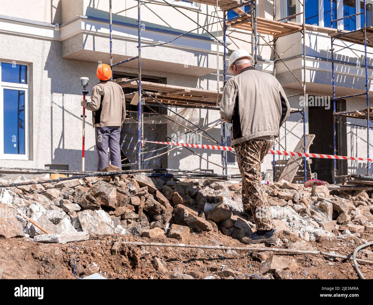 at the construction site, a man in a hard hat looks up fearing a heavy ...