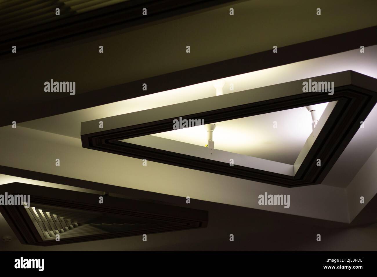 Triangular lamp in interior. Design of lighting device. Lamp on ceiling ...