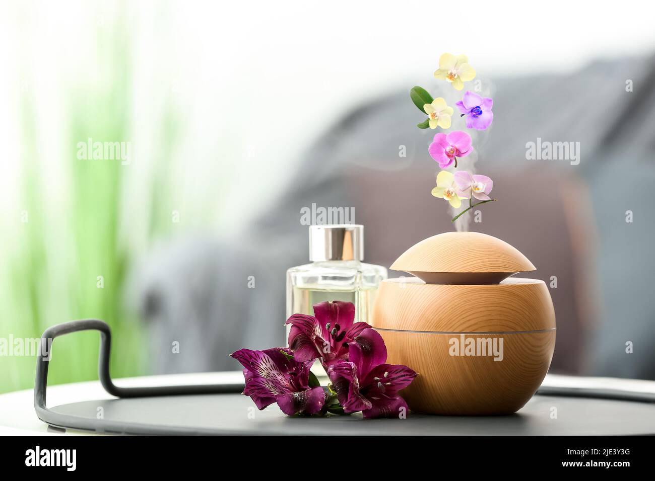 Aroma oil diffuser with flying orchid flowers on table in room Stock ...